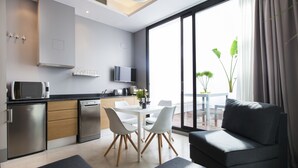 Cozinha moderna com área de refeições, sofá e uma grande janela com vista para o verde.