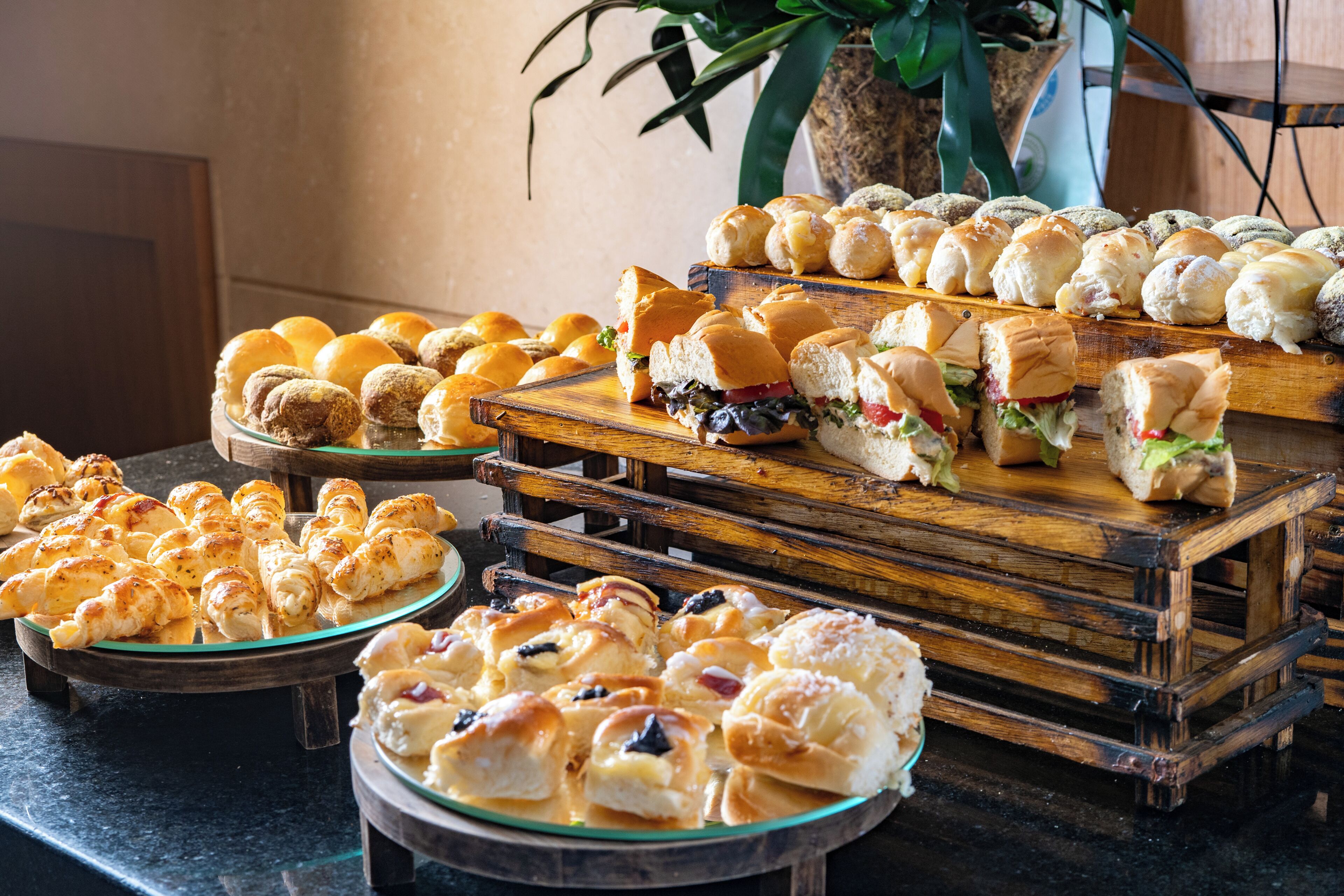 Uma mesa de buffet com diversos pães e sanduíches.