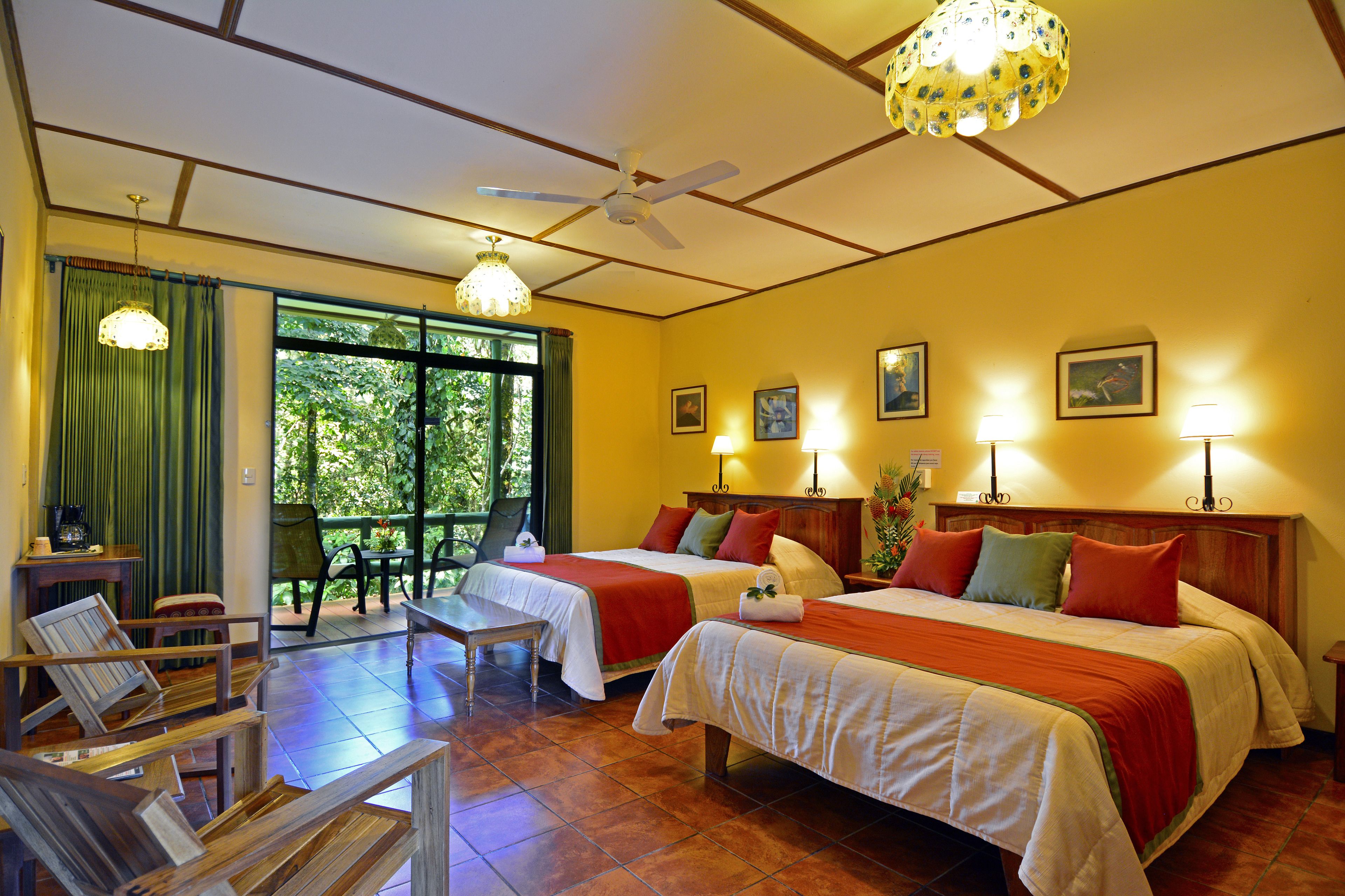 Quarto de hotel com duas camas, um espaço de refeições e vista para o exterior.