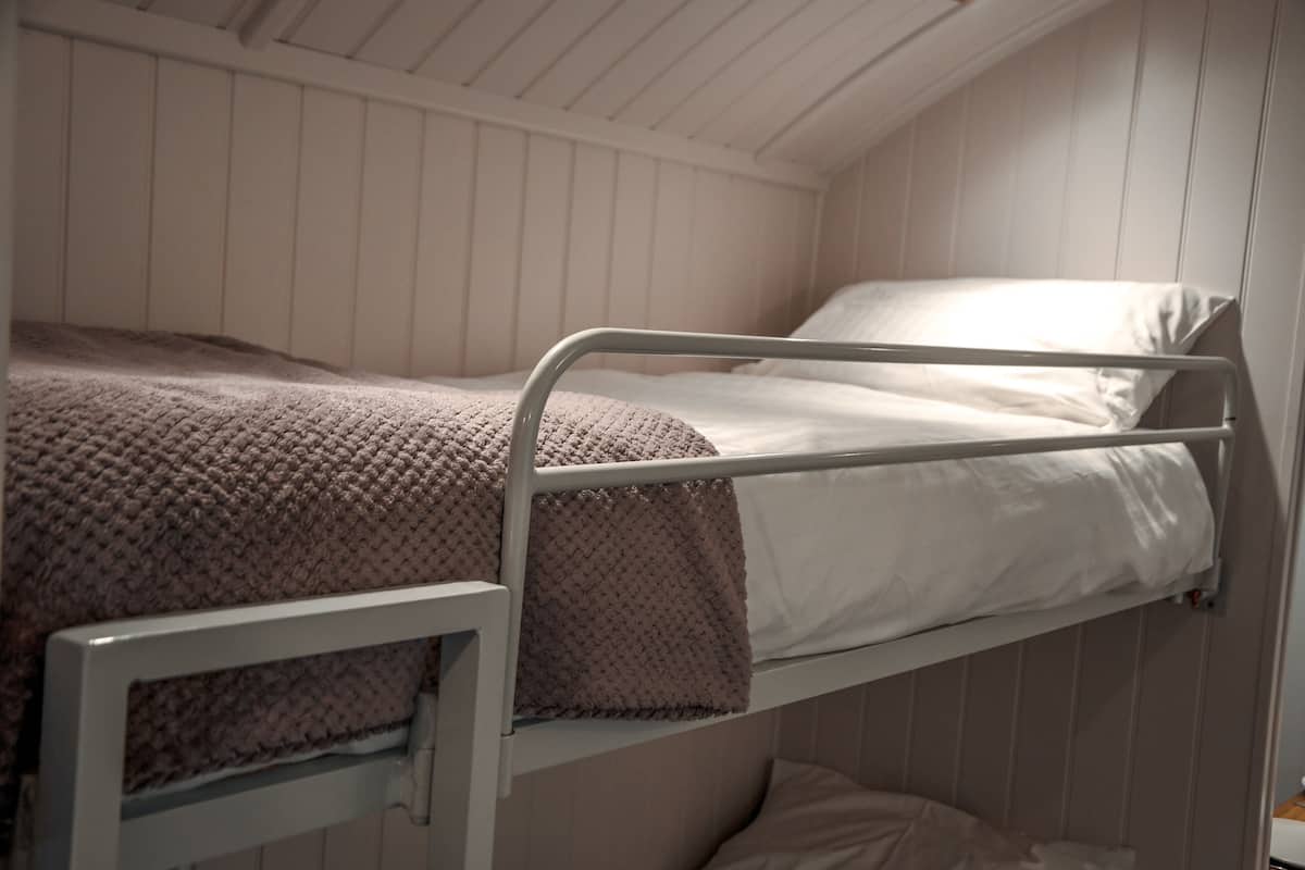 Uma cama beliche com estrutura de metal e roupa de cama branca.