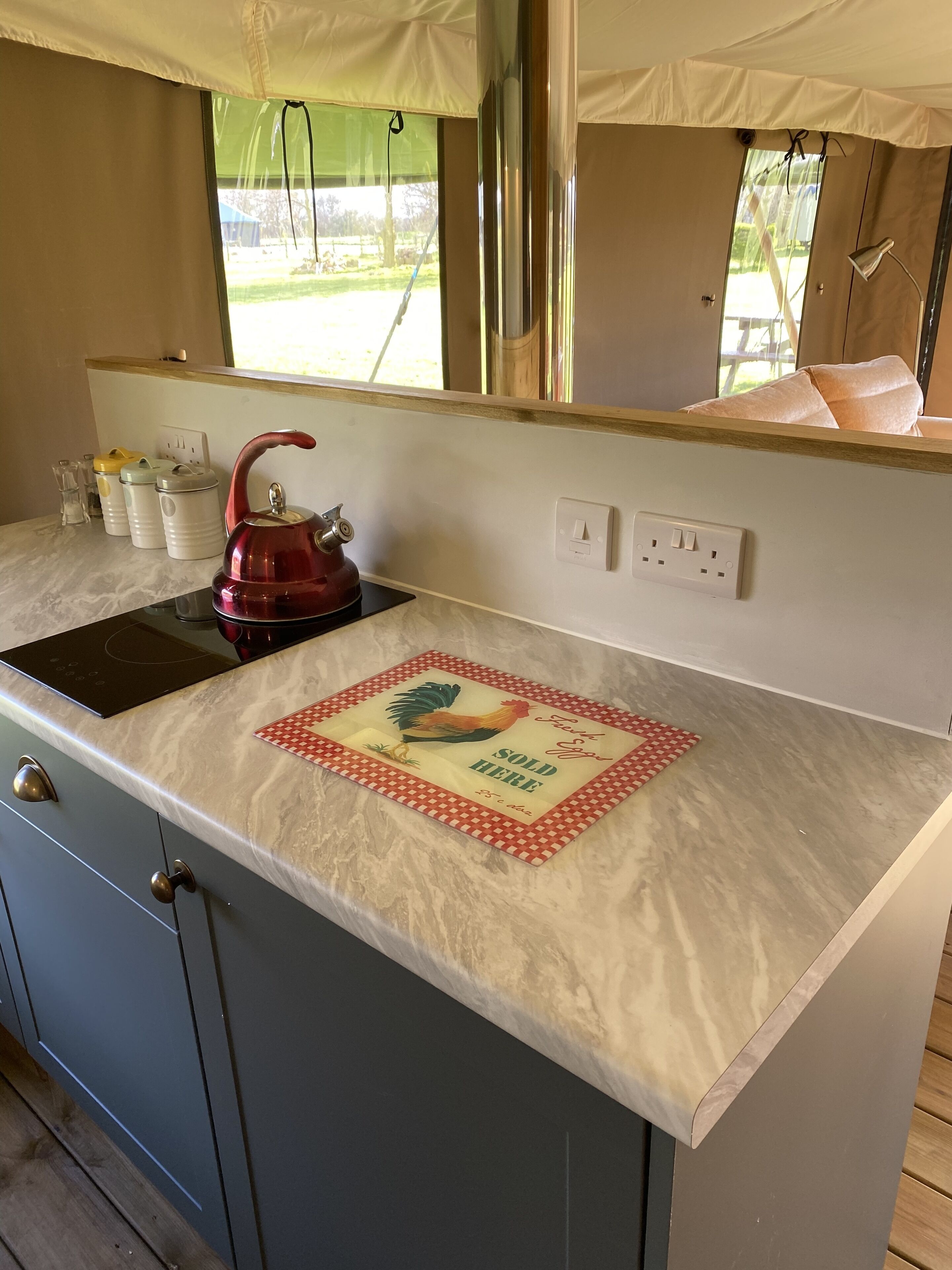 Cozinha com bancada, chaleira e janela.