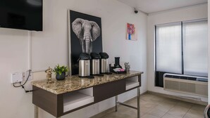 Uma cozinha com bancada de granito, cafeteira, torradeira e uma planta em vaso.