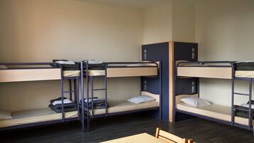 Um quarto de dormitório com beliches, uma mesinha e um armário.