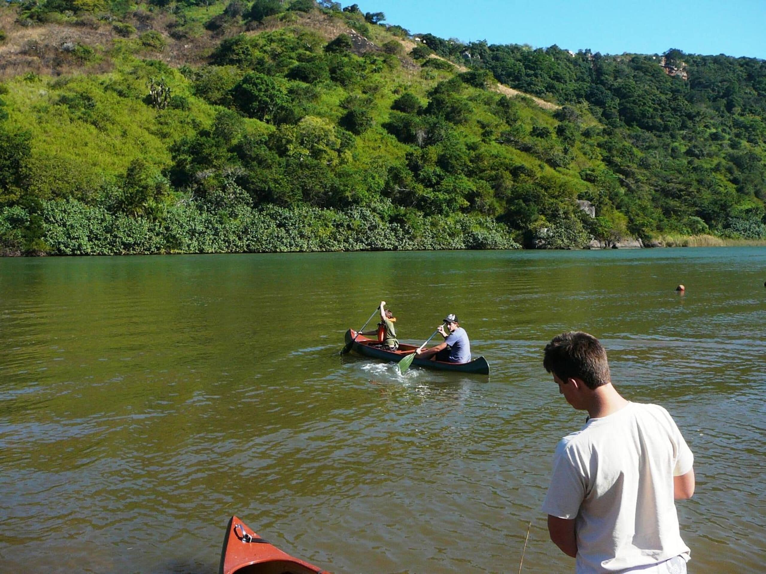 Um grupo de pessoas em um barco a remo em um rio, cercado por vegetação exuberante.