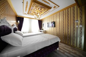 Quarto de hotel luxuoso com uma cama grande, teto ornamentado e uma televisão.
