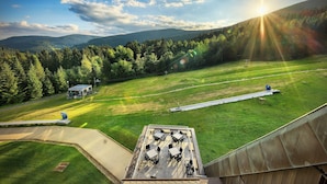 Terraço no telhado com área de estar ao ar livre e vista para um campo verde e colinas arborizadas.