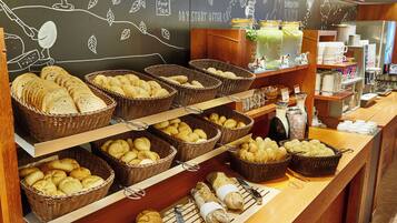 Buffet de café da manhã com diversos pães e doces dispostos em cestas.