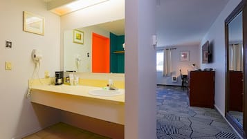 Um banheiro de hotel com pia, espelho e secador de cabelo.