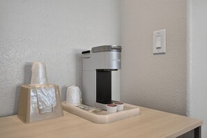 Máquina de café com reservatório de água e porta-copos em bancada.