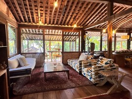 Um quarto acolhedor com teto de madeira, um sofá, uma mesa de centro e uma poltrona estampada.