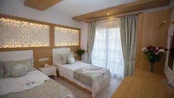 Quarto de hotel com duas camas, teto de madeira, mesa de cabeceira com telefone e um vaso com flores.