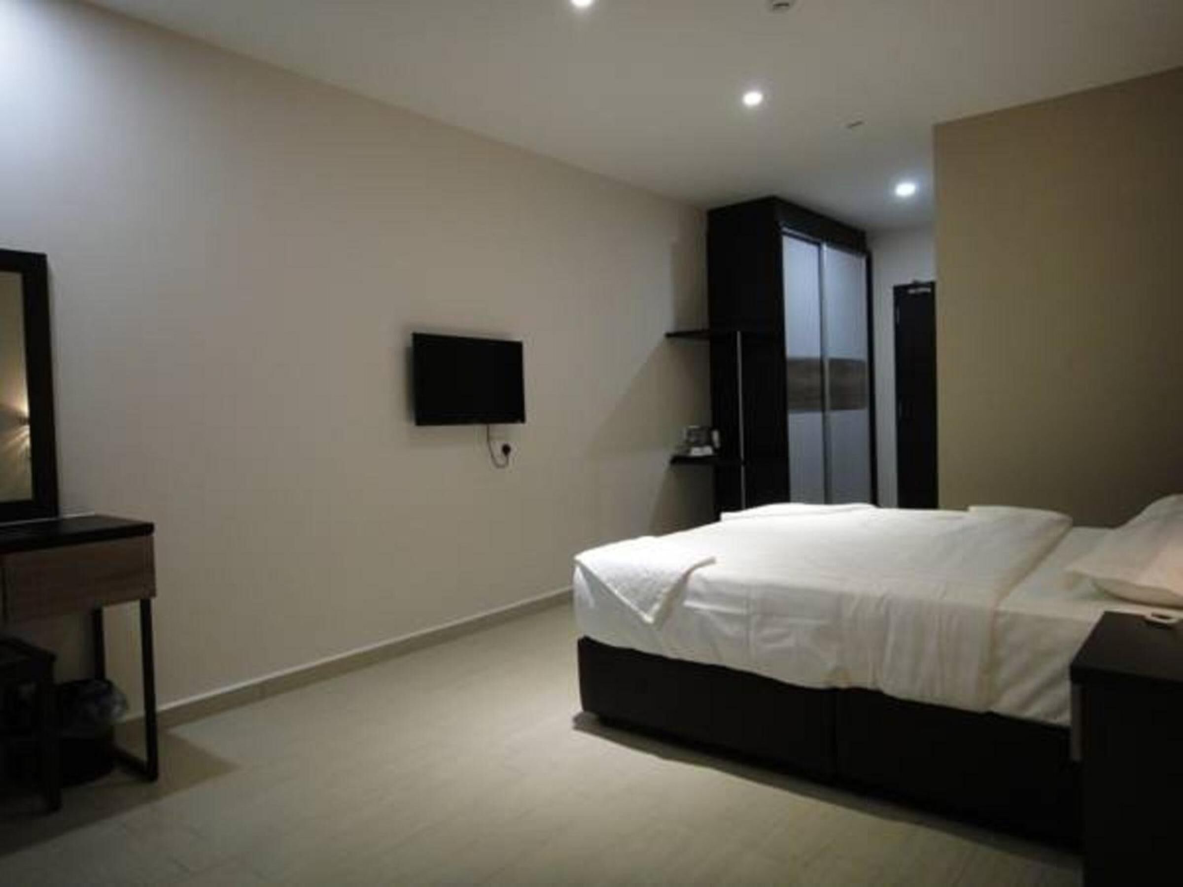 Quarto com cama, televisão na parede e guarda-roupa.