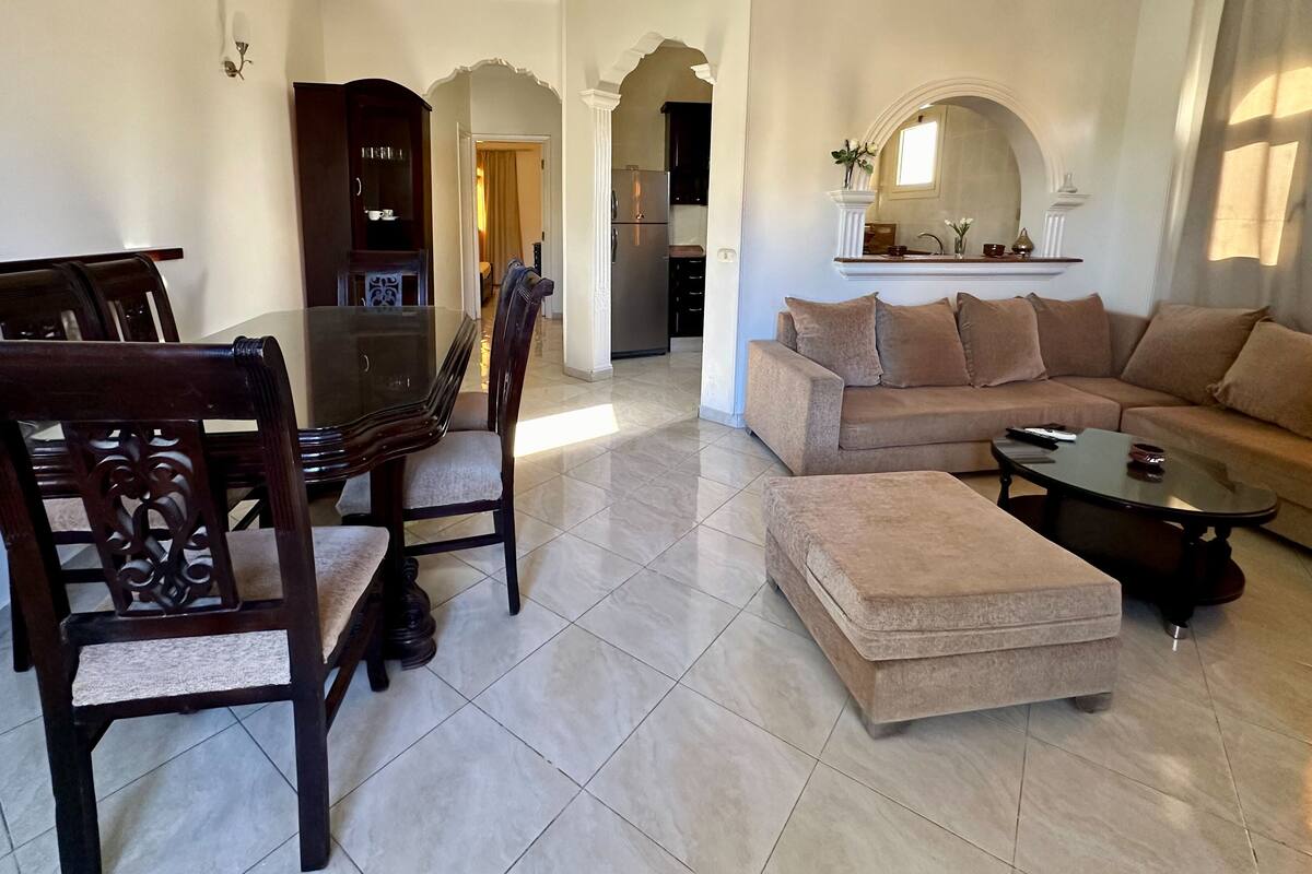 Uma sala de estar com uma mesa de jantar, cadeiras, um sofá e uma mesa de centro.