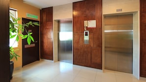 Área de elevador moderna com painéis de madeira e uma placa indicando a localização.