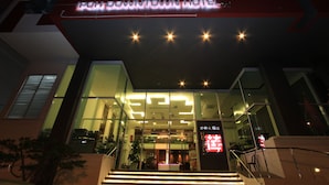 Exterior do Port Town Hotel com design moderno, apresentando fachada de vidro, escadaria que leva à entrada e um letreiro chamativo acima da entrada.