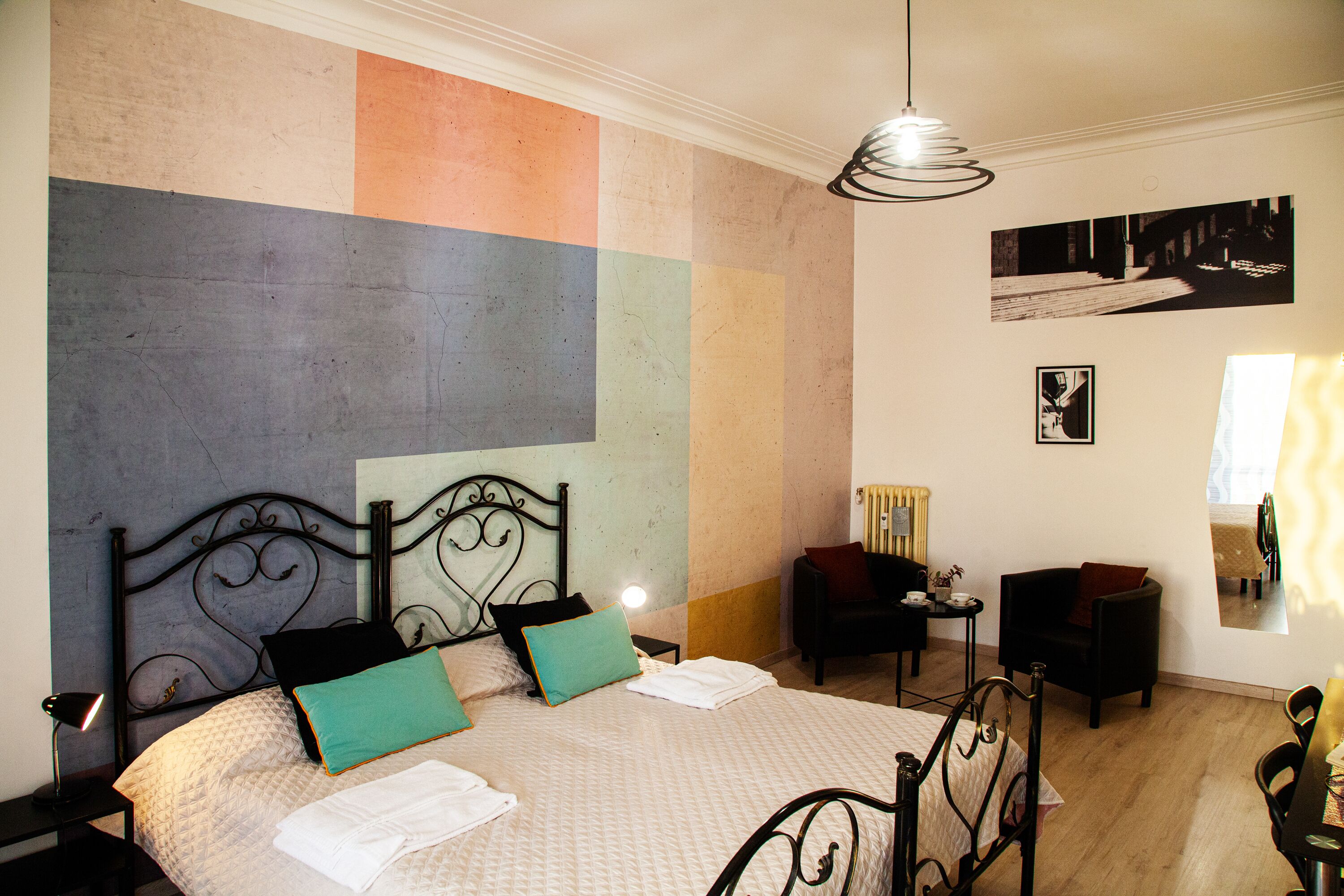 Quarto com uma cama, mesas de cabeceira, uma cadeira e um espelho.