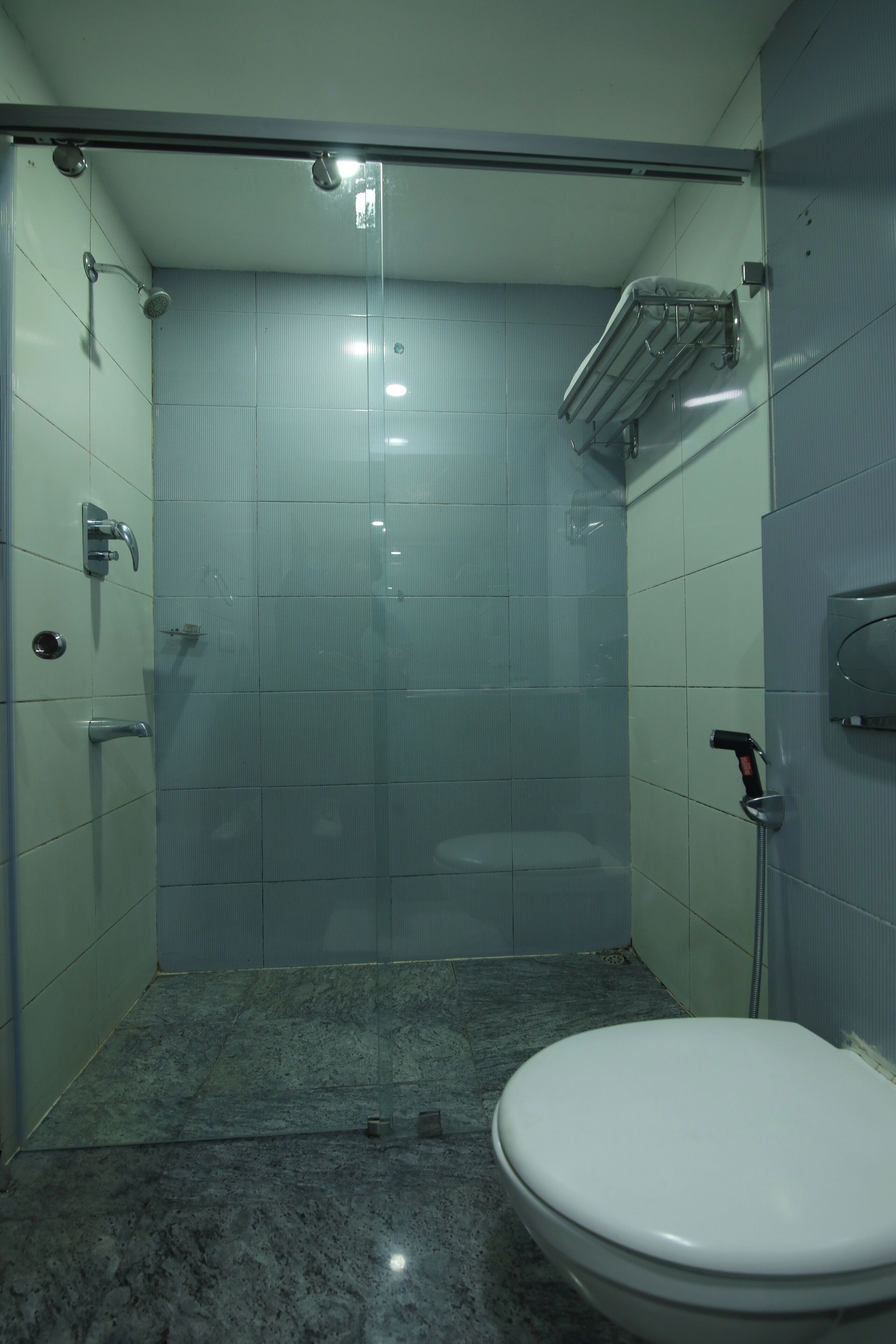 Uma casa de banho pequena e moderna, com cabine de duche em vidro, sanita branca e barra de toalhas.
