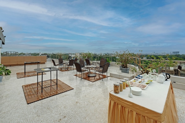 Terraço no telhado com área de estar ao ar livre, mesa de xadrez e mesa de buffet.