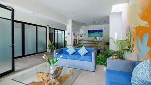 Uma sala de estar moderna com um sofá azul, uma mesa de centro de vidro e um mural na parede.