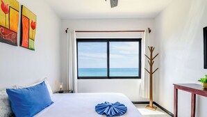 Quarto de hotel com cama grande, vista para o mar e um cabideiro.