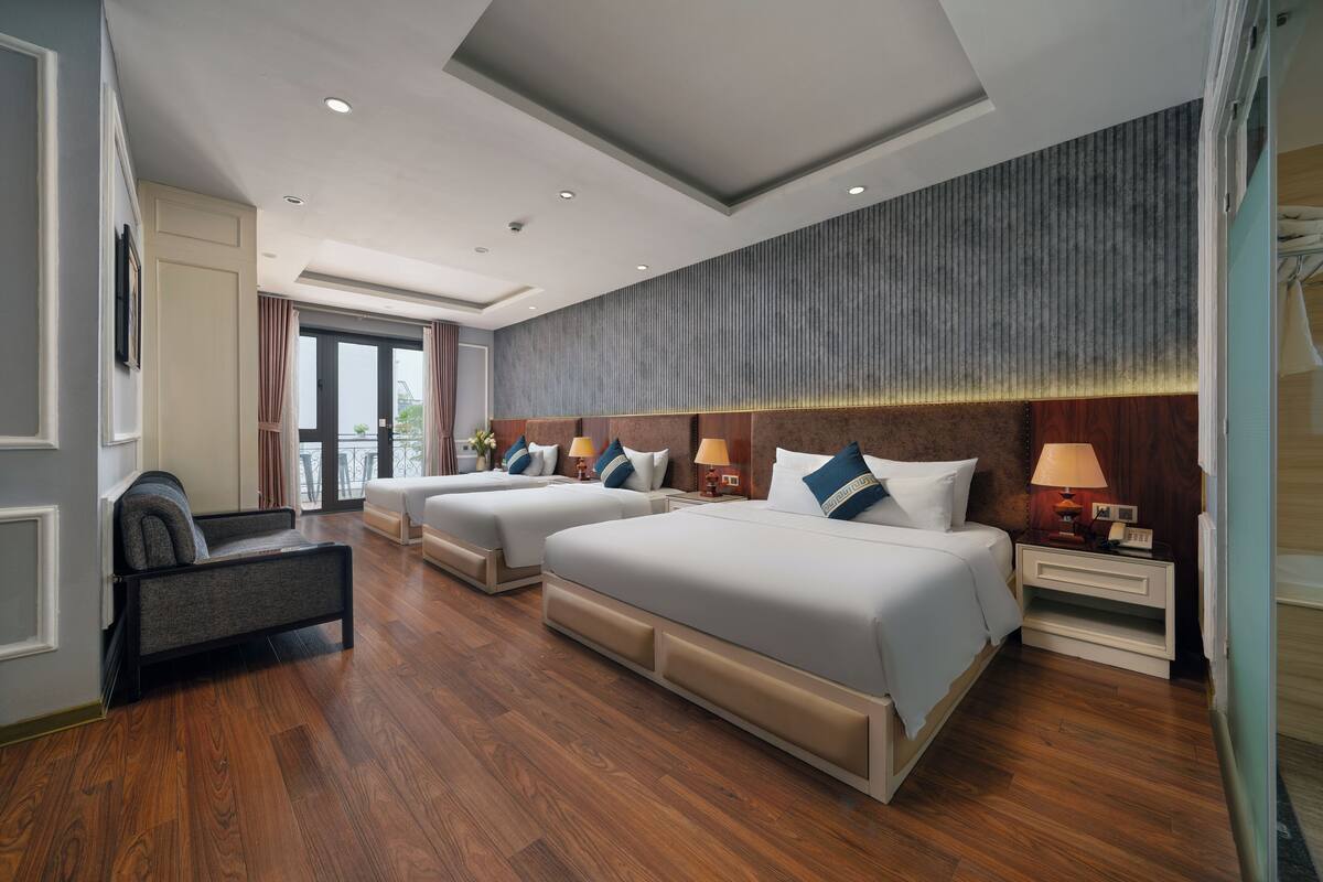 Quarto de hotel com duas camas, uma mesa de trabalho e vista para o exterior.