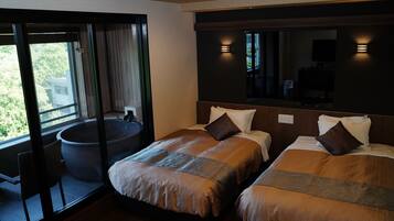 Quarto de hotel com duas camas, uma banheira grande e uma porta de vidro deslizante para uma varanda.
