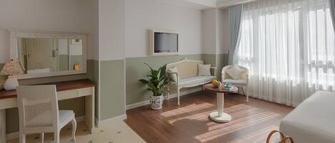Quarto de hotel com escrivaninha, cadeira, cama e uma pequena mesa com uma planta.