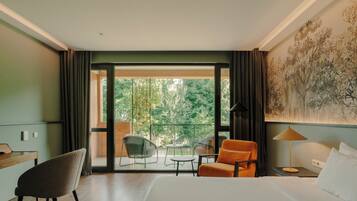 Quarto de hotel com cama, escrivaninha, cadeira, mesa e varanda com cadeiras.