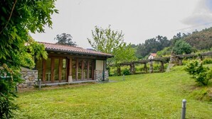 Uma casa com fachada de pedra, grandes janelas e telhado em telhas.