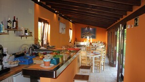Cozinha com ilha central, cadeiras de madeira e chão de azulejos de pedra.