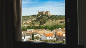 Vista de um castelo numa colina, sobre um lugar com edifícios tradicionais.