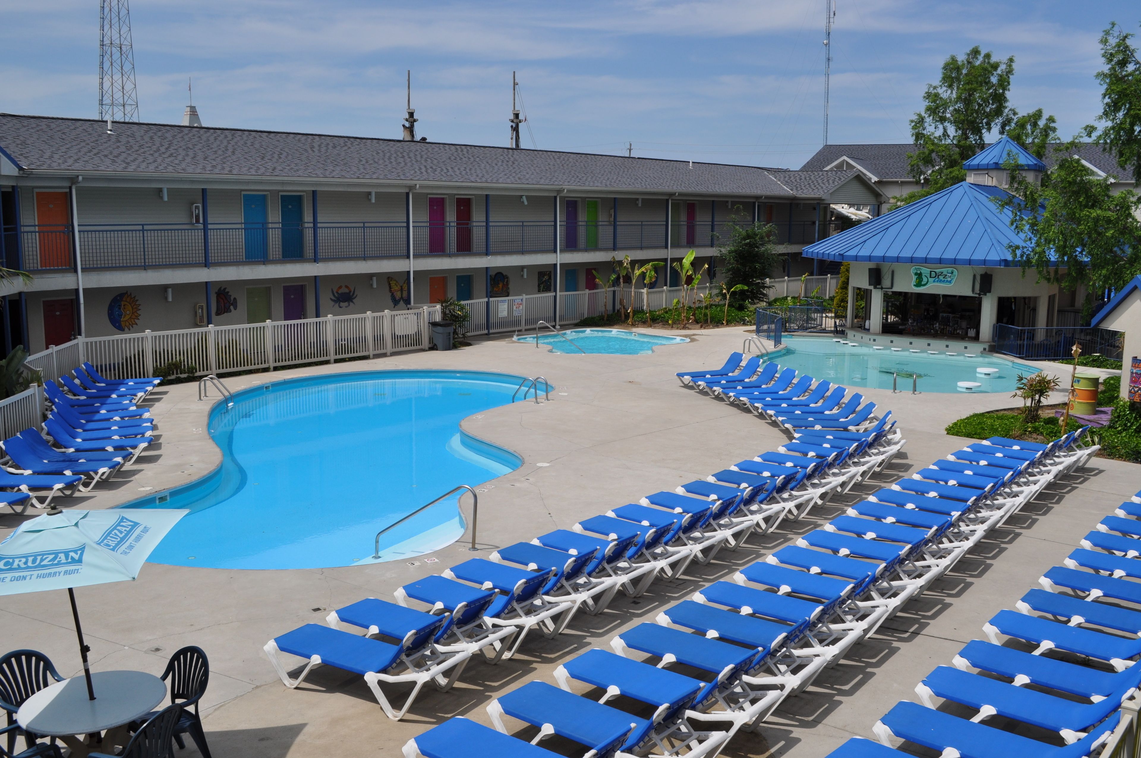Uma área de piscina com várias espreguiçadeiras azuis e uma piscina pequena.