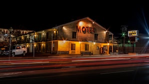 Um edifício de tijolos com uma placa que diz 'Motel' e uma placa de neon para 'Relax Inn' à direita.