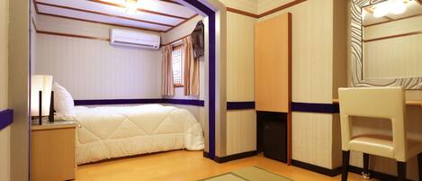 Quarto de hotel com cama, escrivaninha, cadeira, espelho e janela com cortinas.