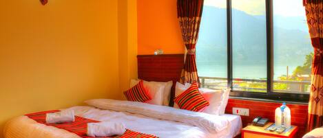 Quarto de hotel com duas camas, janela com vista para o mar e mesa de cabeceira com telefone e garrafa.