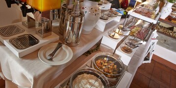 Disposição de buffet com diversos alimentos e utensílios para servir.