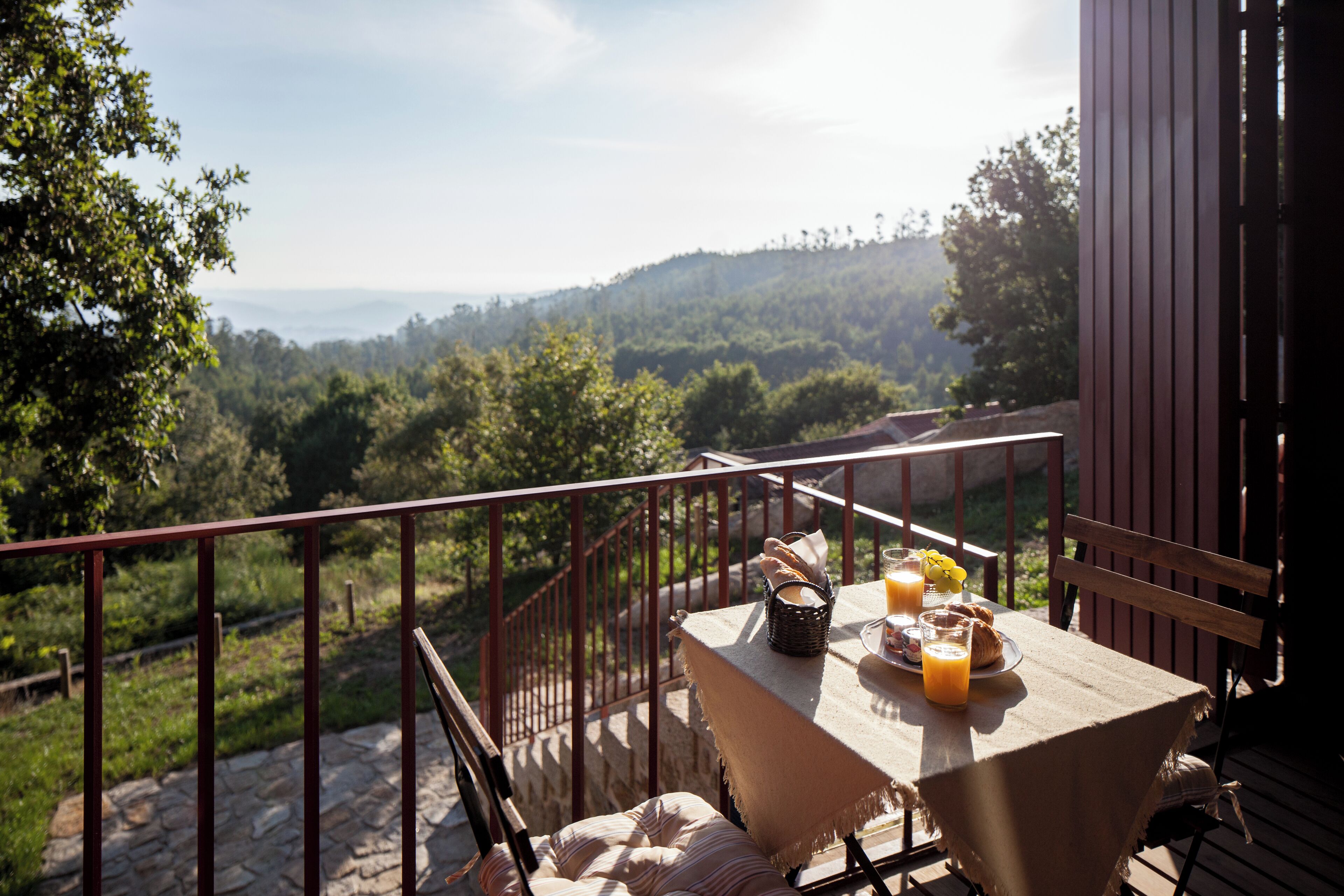Varanda com mesa posta para o café da manhã, com vista para uma paisagem deslumbrante.