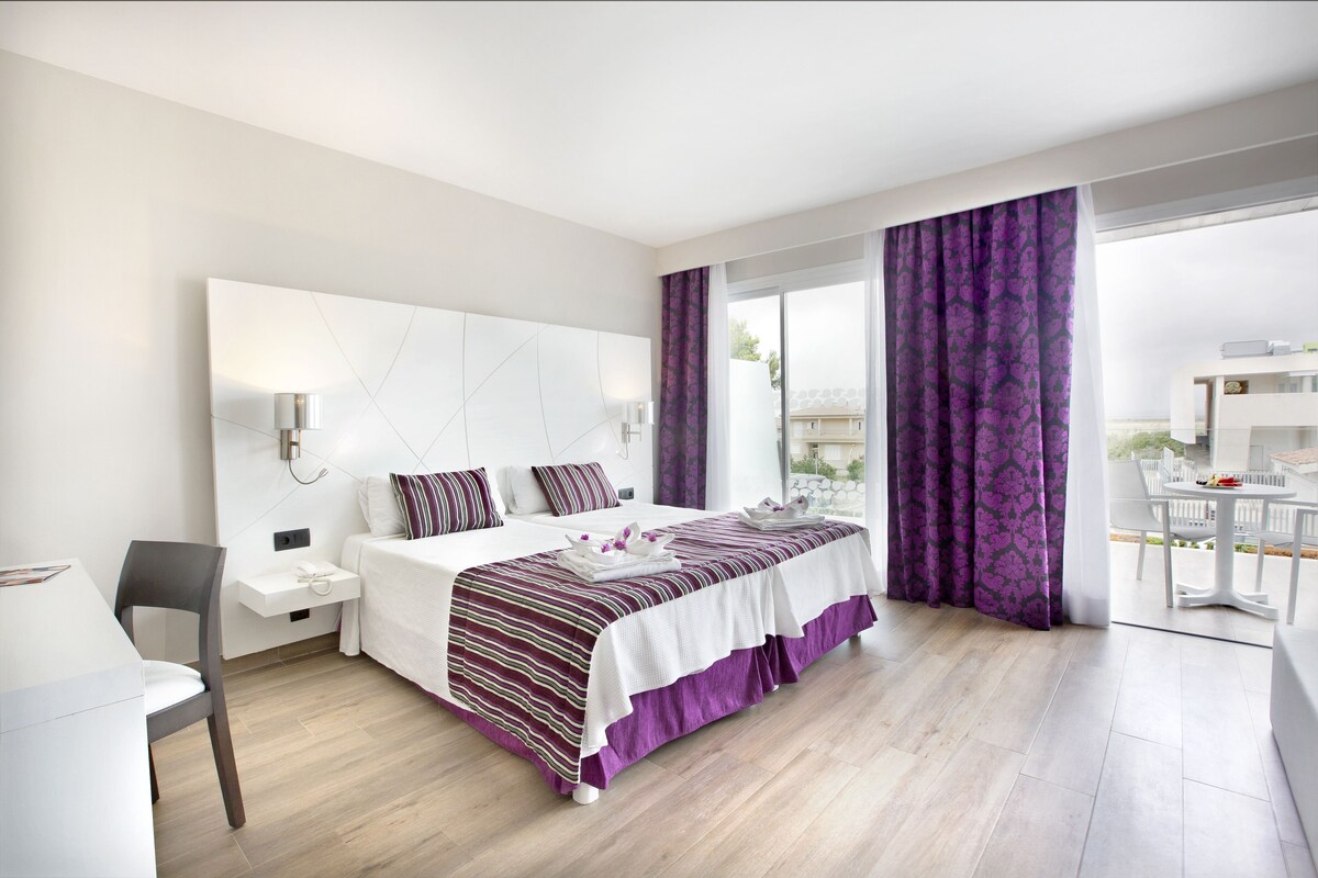 Quarto de hotel moderno com uma cama grande, uma mesa e uma cadeira.