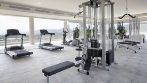 Uma academia com esteiras, elípticos, um banco e equipamentos de musculação.