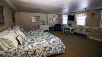 Quarto com cama grande, escrivaninha, cadeira e televisão.