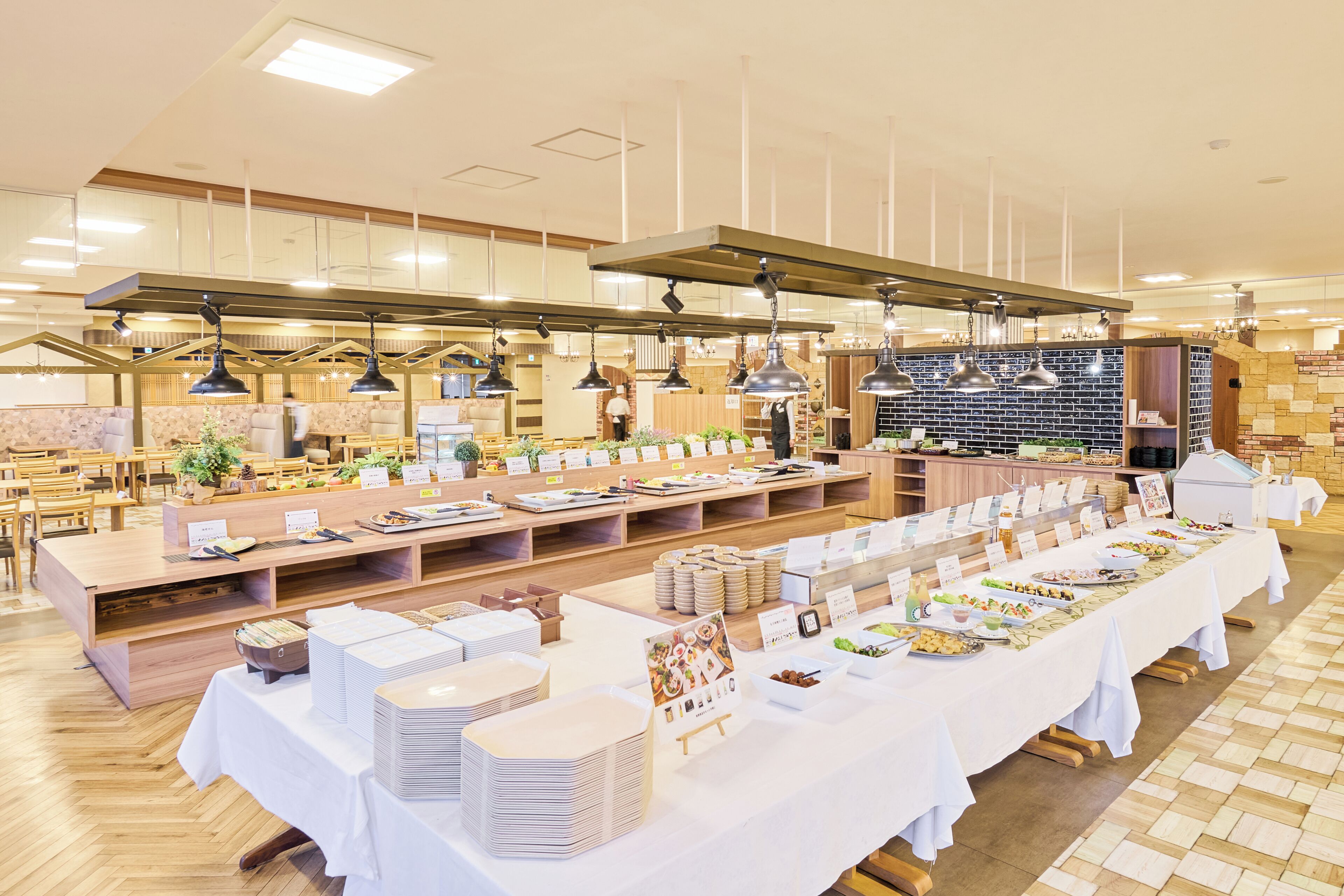 Buffet montado com diversas estações de serviço, grande variedade de alimentos e interior moderno e impecável.