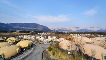 Uma vila com casas em formato de cúpula, uma estrada sinuosa e montanhas ao fundo.