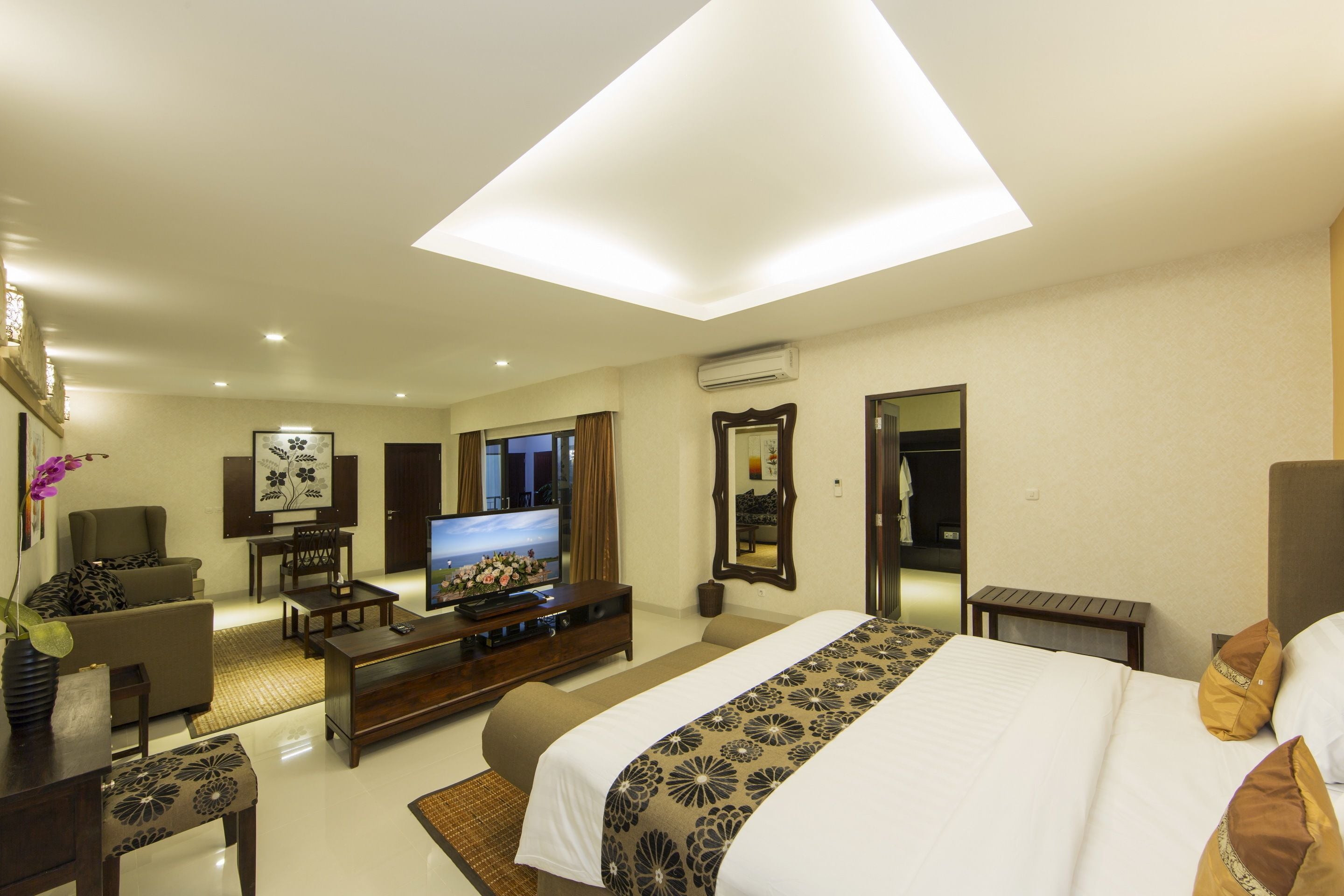Quarto de hotel com cama, televisão, sofá, mesa de centro e escrivaninha.