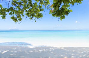 Na praia, areia branca, espreguiçadeiras, toalhas de praia