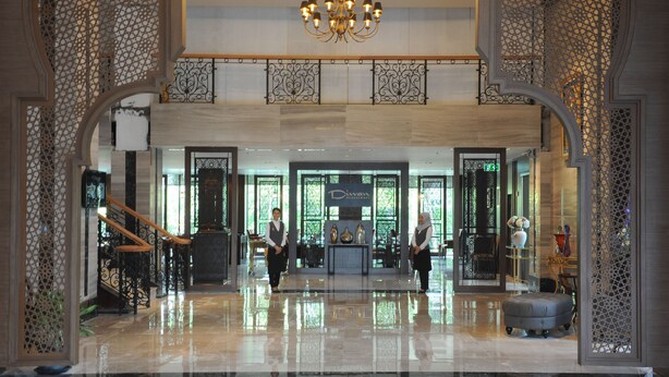 Um hall amplo com um candelabro, uma receção e uma escadaria.