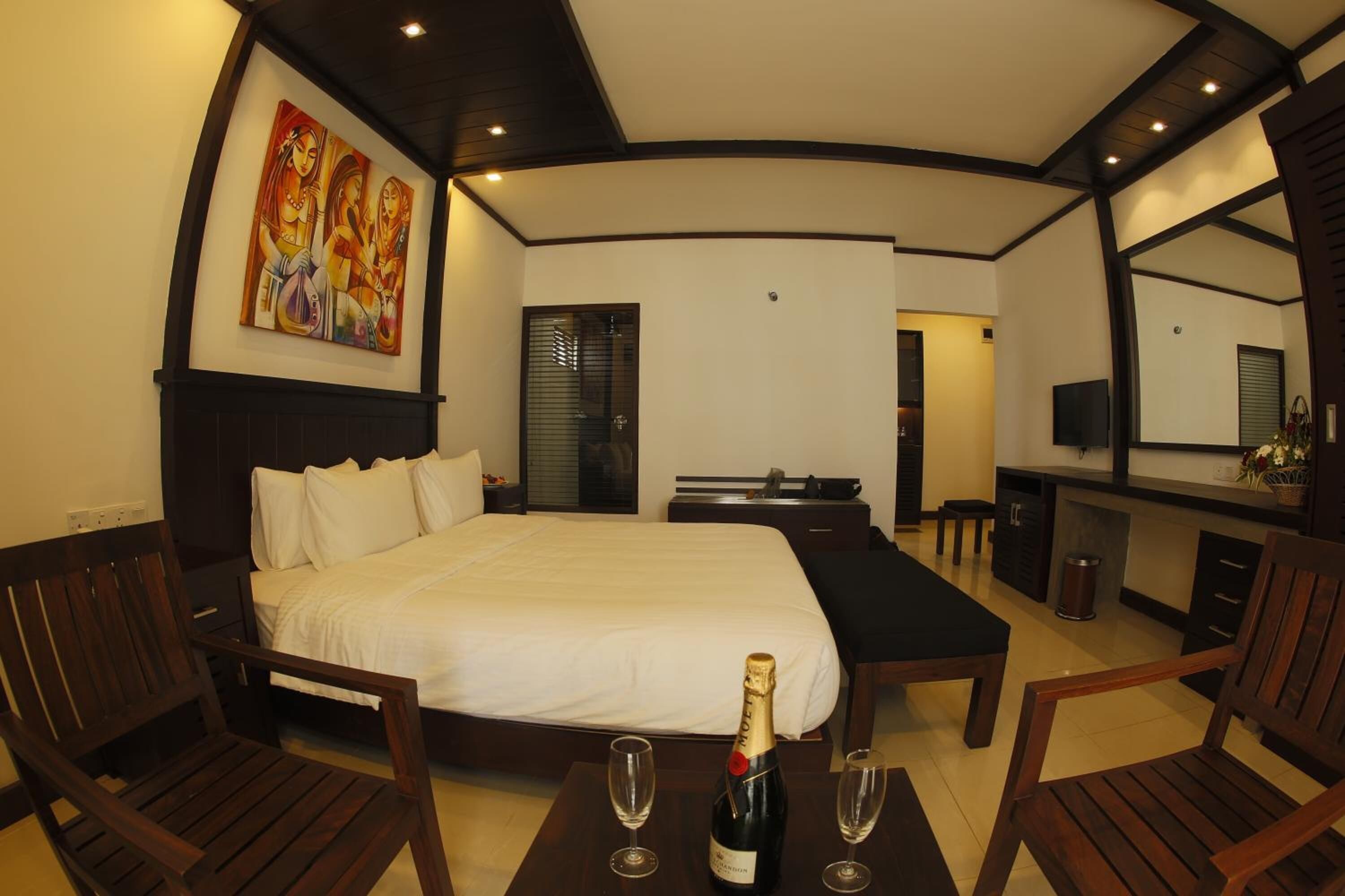 Quarto de hotel com uma cama grande, uma escrivaninha, uma cadeira e uma garrafa de champanhe.