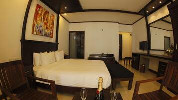 Quarto de hotel com uma cama grande, uma escrivaninha, uma cadeira e uma garrafa de champanhe.