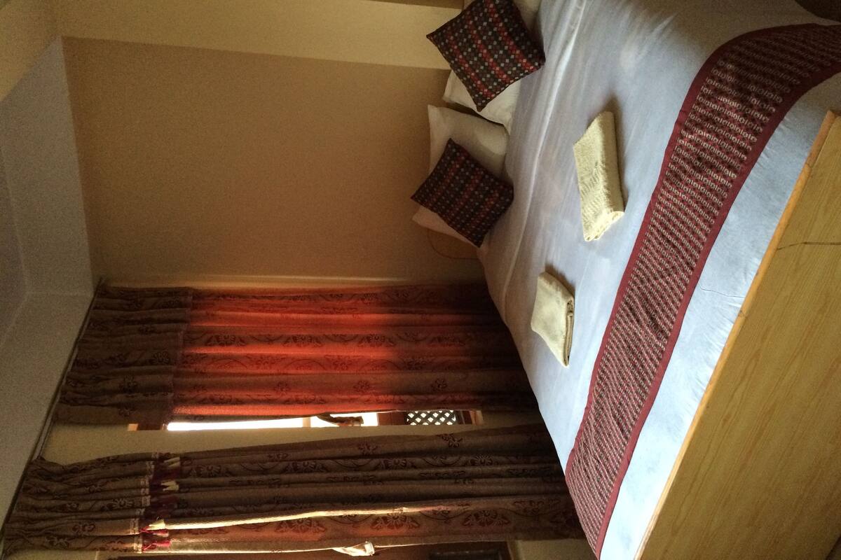 Quarto com cama, cortinas estampadas e cabeceira de madeira.