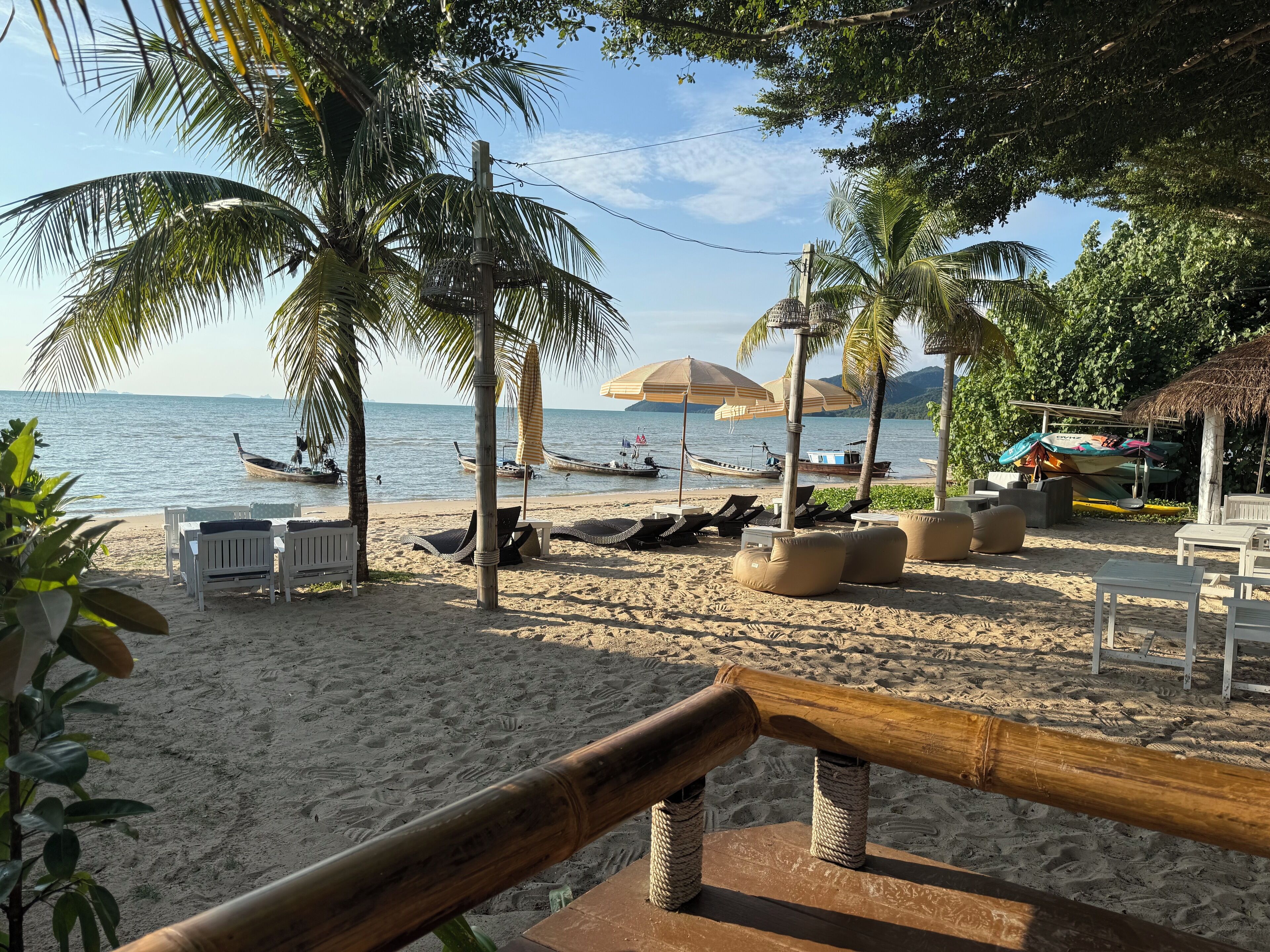 Uma praia com cadeiras de praia, guarda-sóis e uma estrutura com telhado de palha.