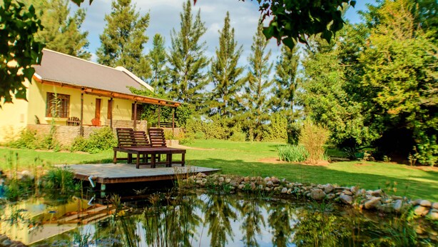 Uma casa com deck, área de estar externa e um lago.